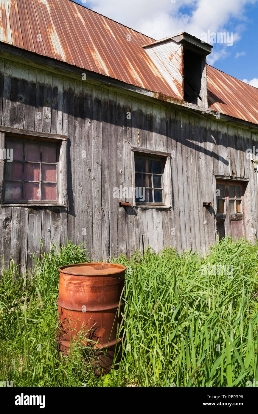 Old grey wooden barn with rusted metal roof and oil drum Stock Photo ...