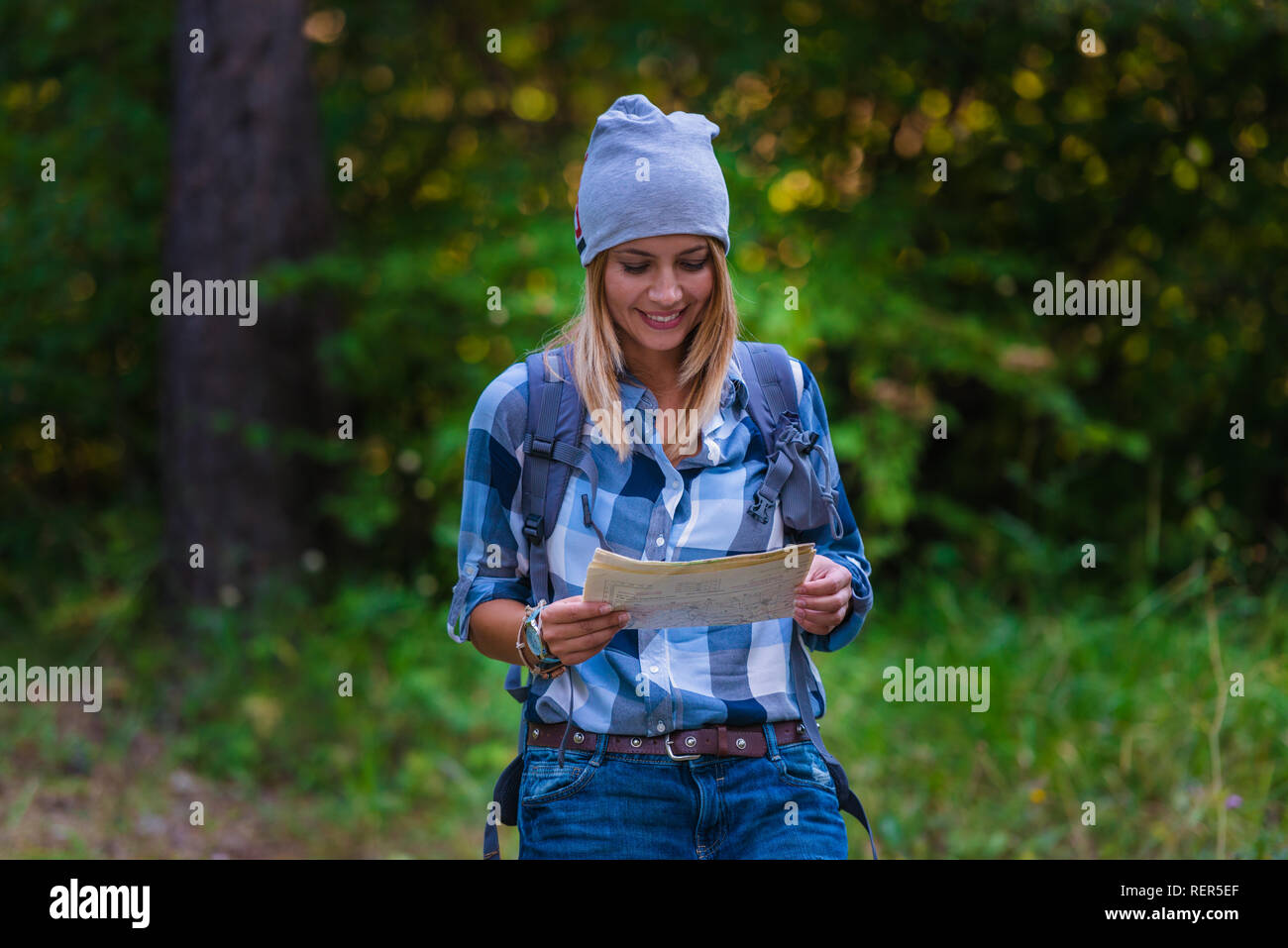 Young woman walking alone in the woods holding a map. Hiking concept in ...