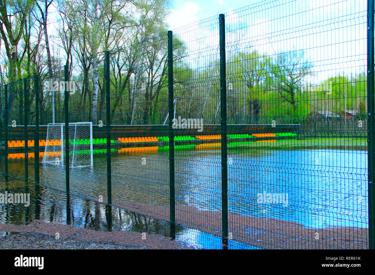 Football field during the flood of river. Small football stadium fenced ...