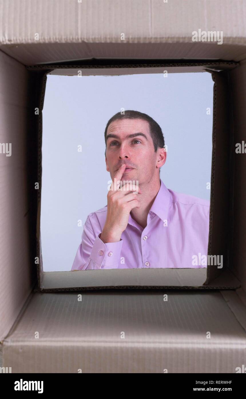 Thoughtful man seen through a box, symbolic for thinking outside the ...