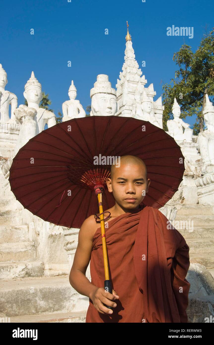 Young Buddhist monk with a red umbrella, Settawya Pagoda, Mingun, Burma ...