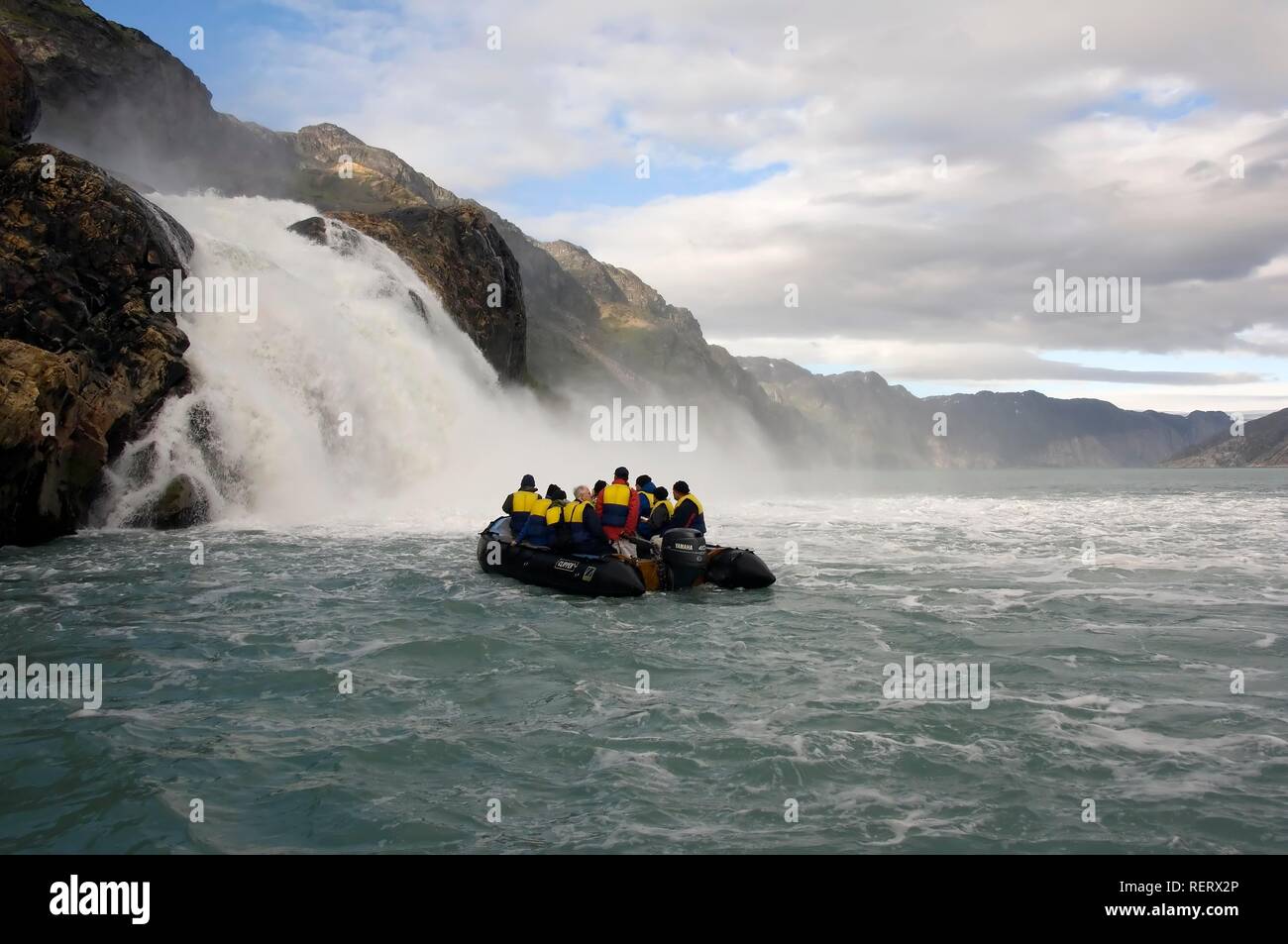 Zodiac with tourists approaching a waterfall, Arsuk Fjord, Greenland ...