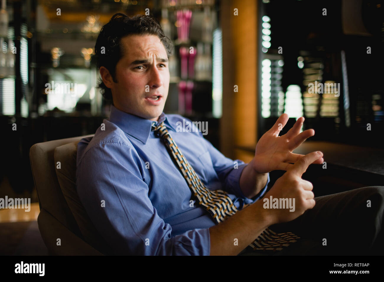 Young businessman explaining while sitting inside a bar Stock Photo - Alamy