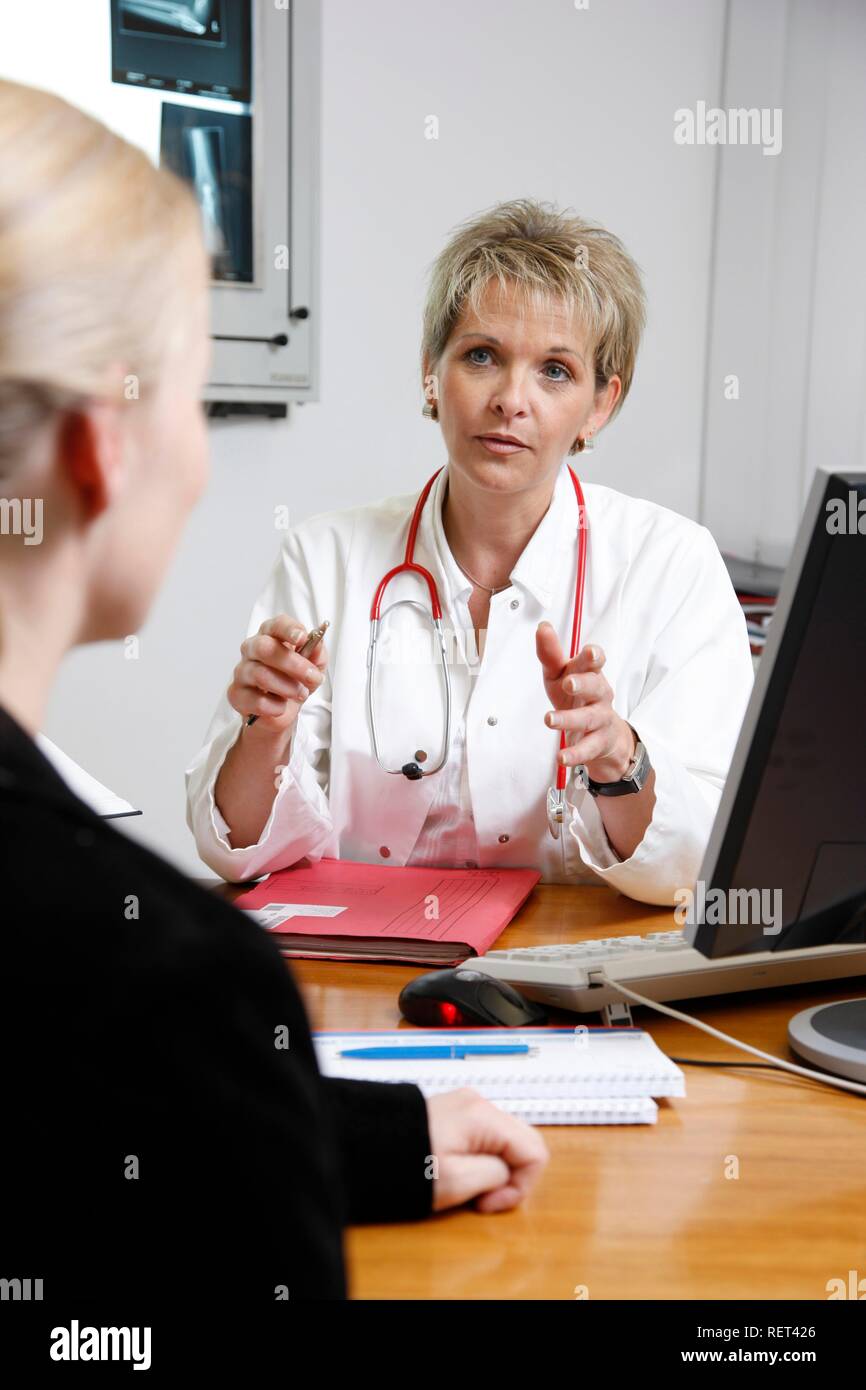 A female doctor talking to a patient in a hospital doctor's office ...