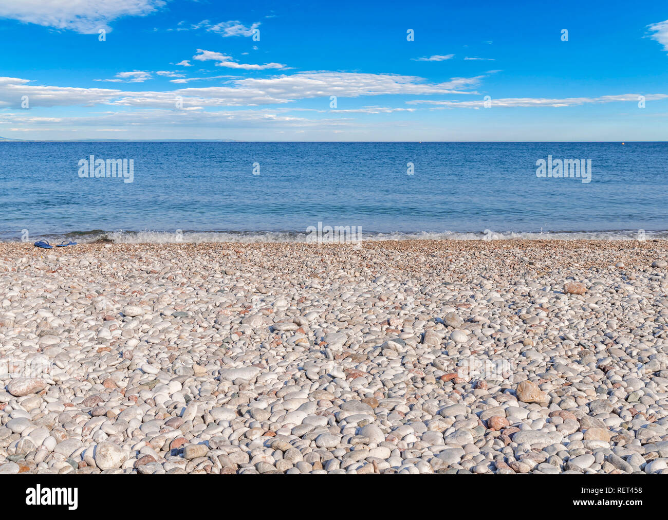 Pebble stone beach with cloudy blue sky Stock Photo - Alamy