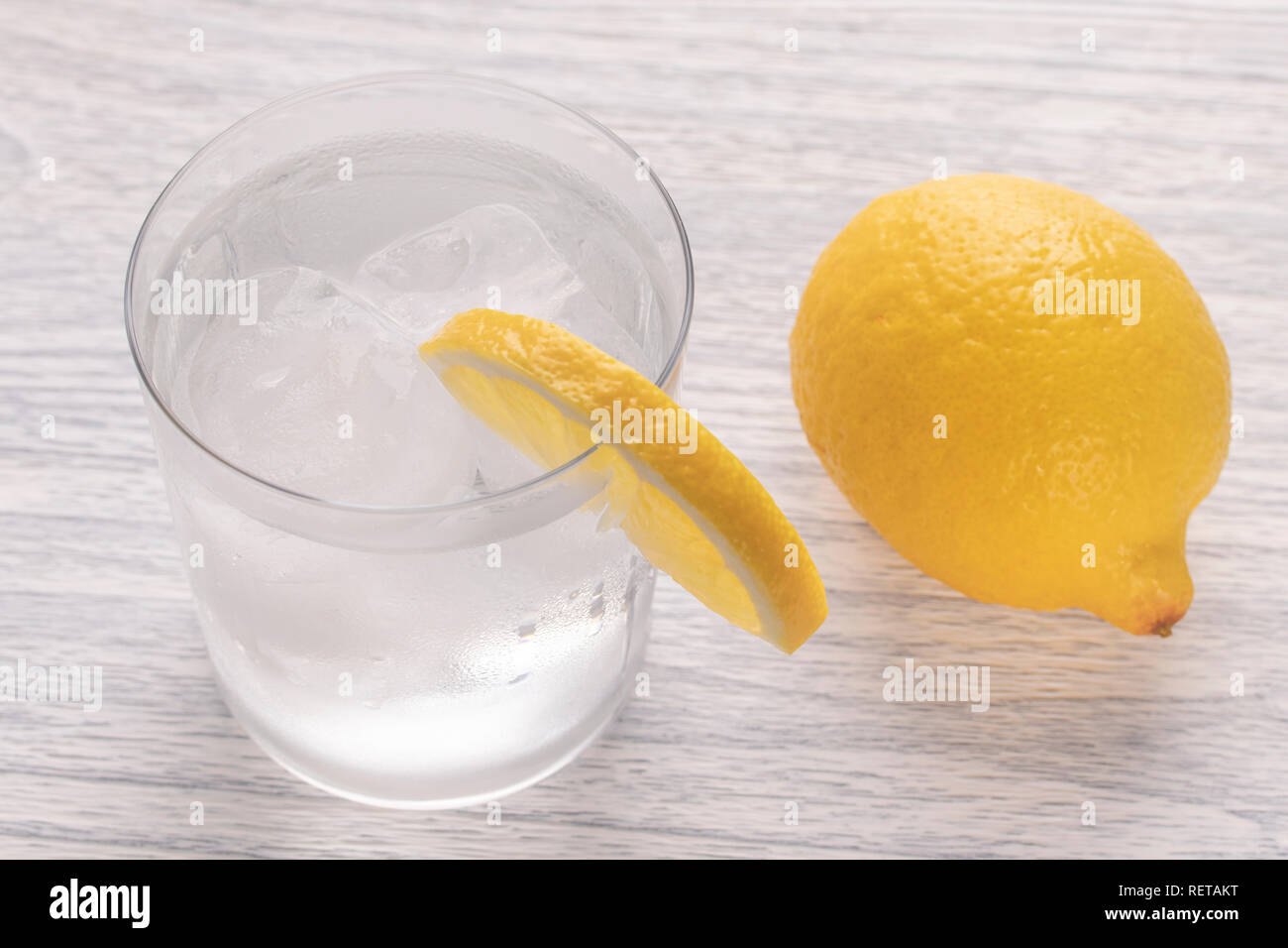 Refreshing cold water with lemon in a wet glass with ice. On a white ...