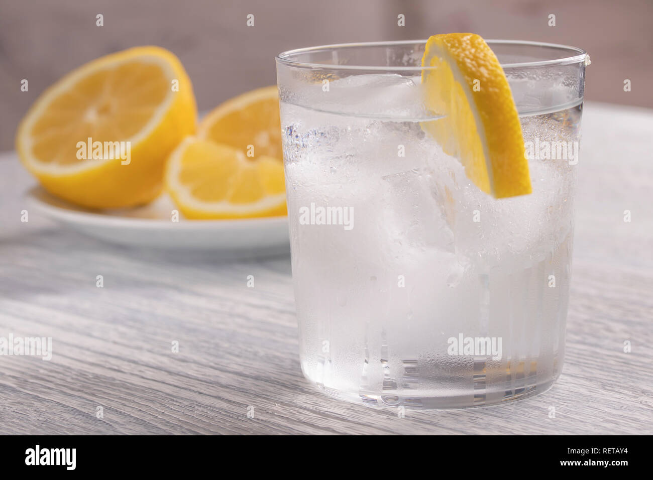 Refreshing cold water with lemon in a wet glass with ice. On a white ...