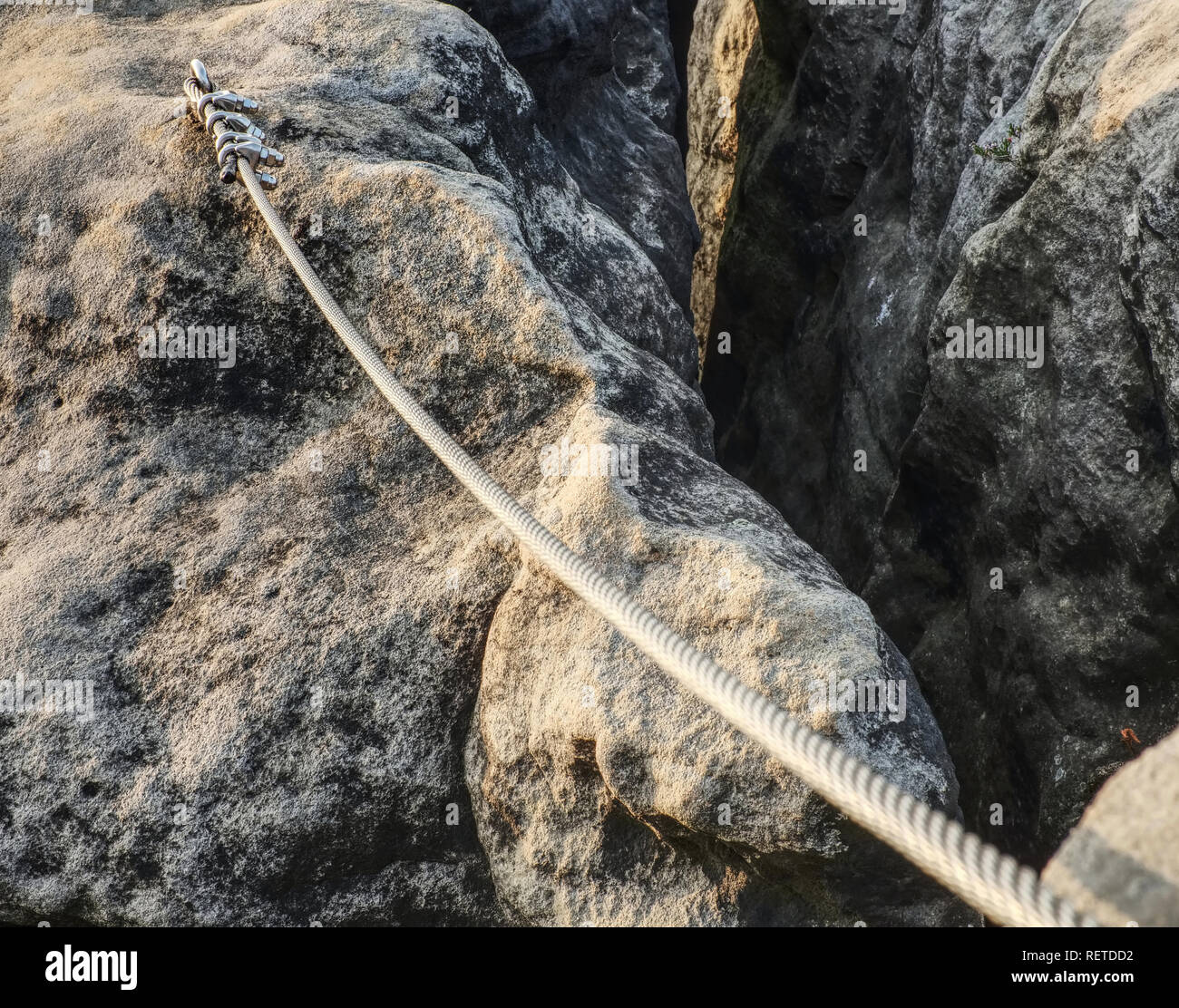 Stainless twisted rope anchored in rocky wall. Stair climbing and iron ...