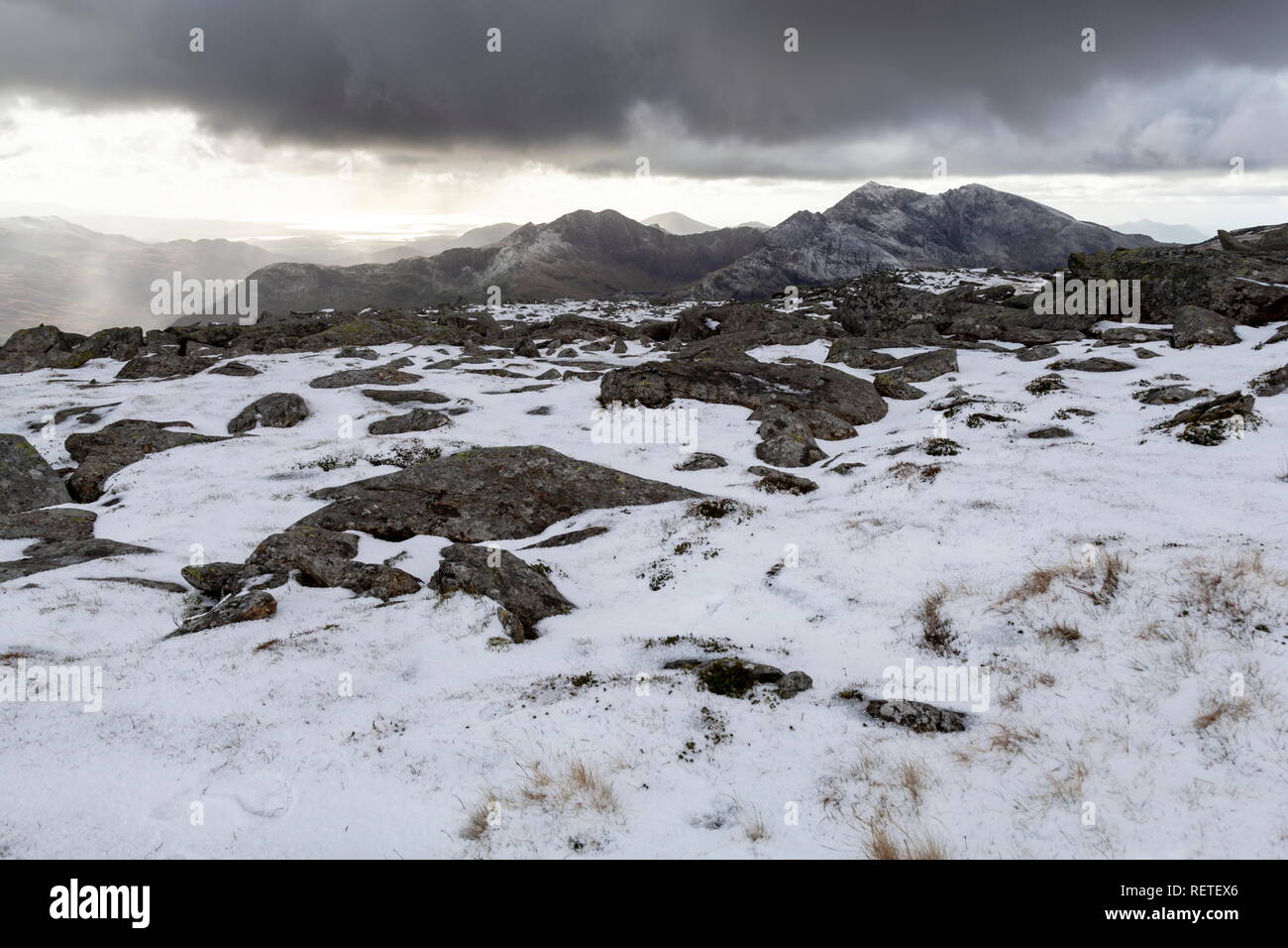 A snow capped Snowdon sit under dark clouds. Viewed from Gylder Fach ...