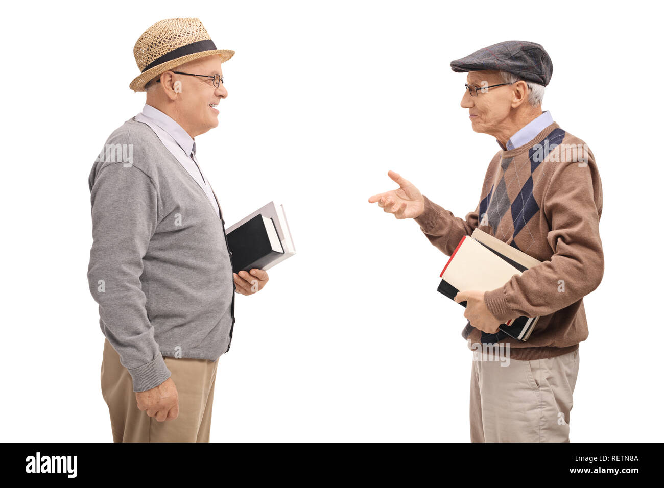 Two senior men holding books and talking isolated on white background ...