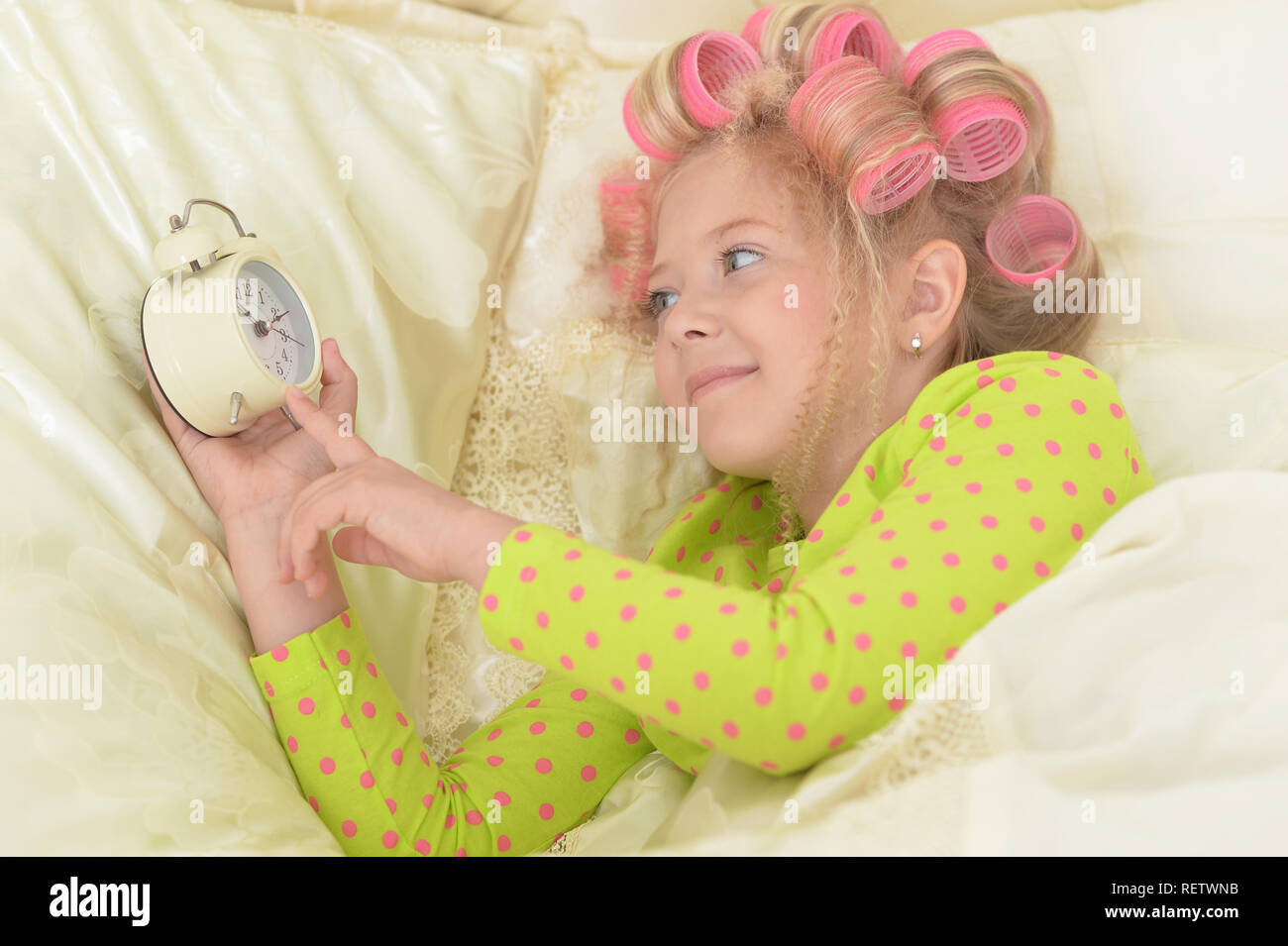 Happy cute little girl in hair curlers awaked Stock Photo - Alamy