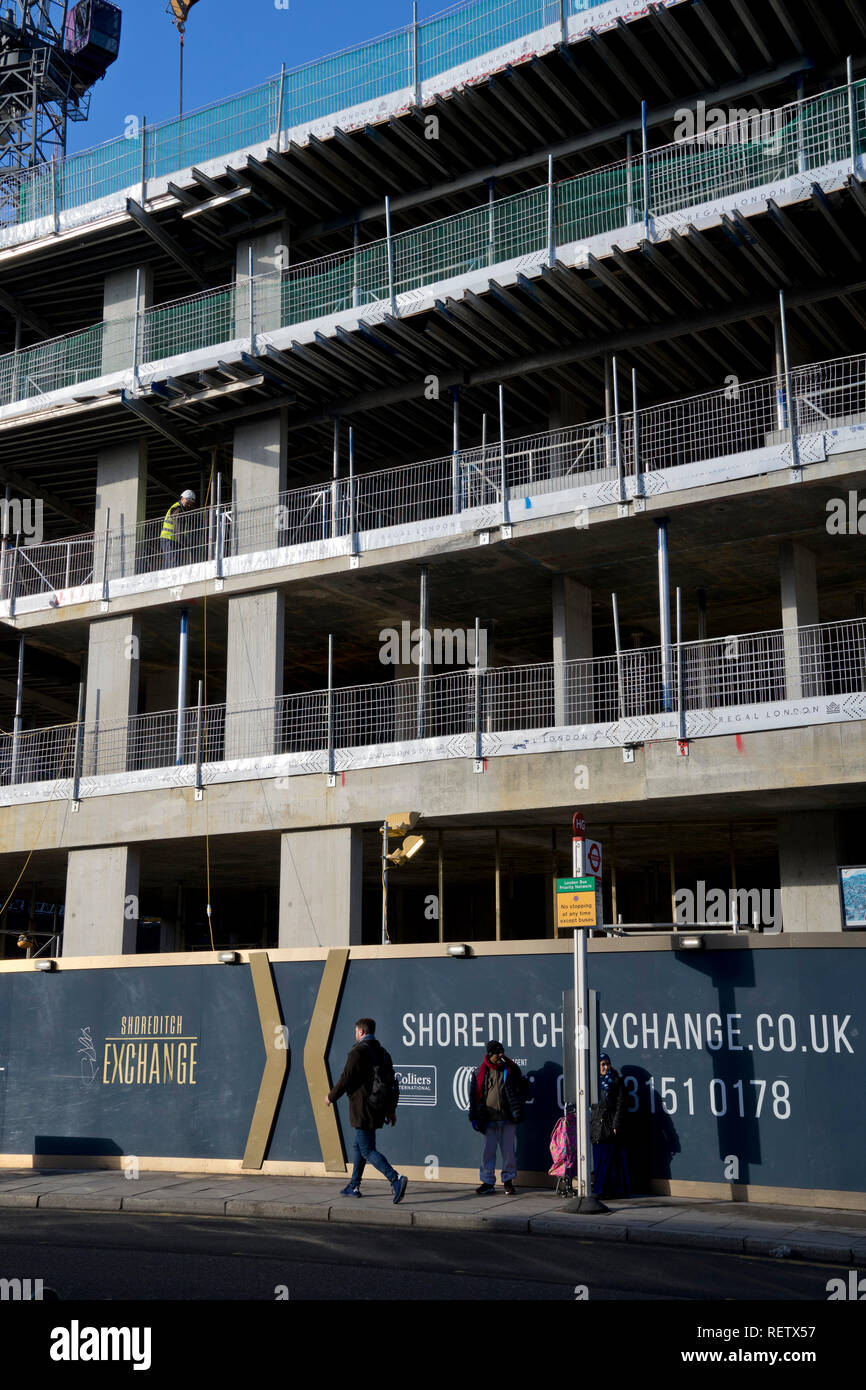 People waiting at a bus stop by a new luxury housing development in ...
