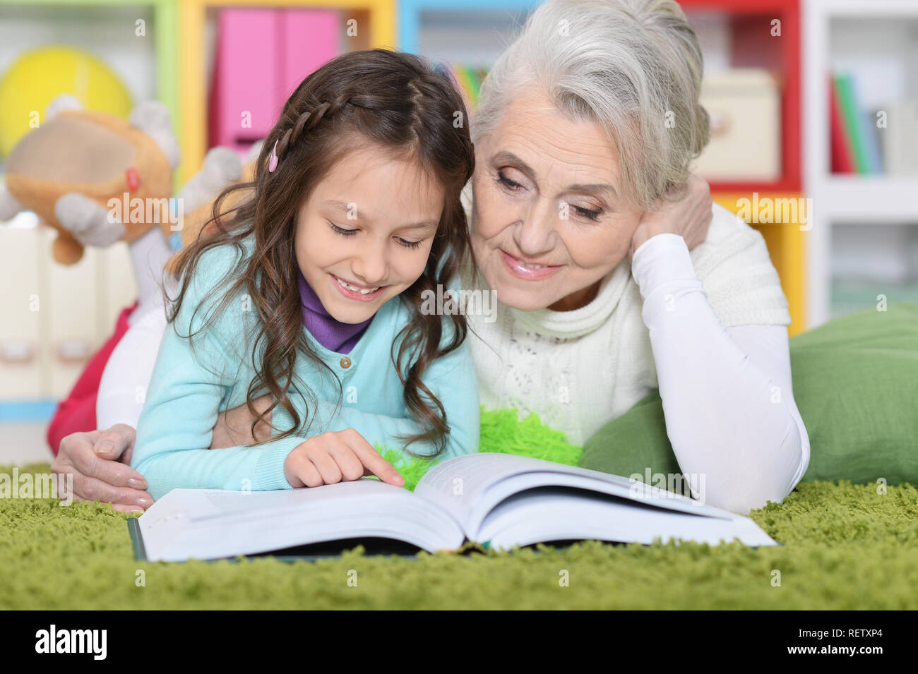Portrait of grandmother reading book with granddaughter Stock Photo - Alamy