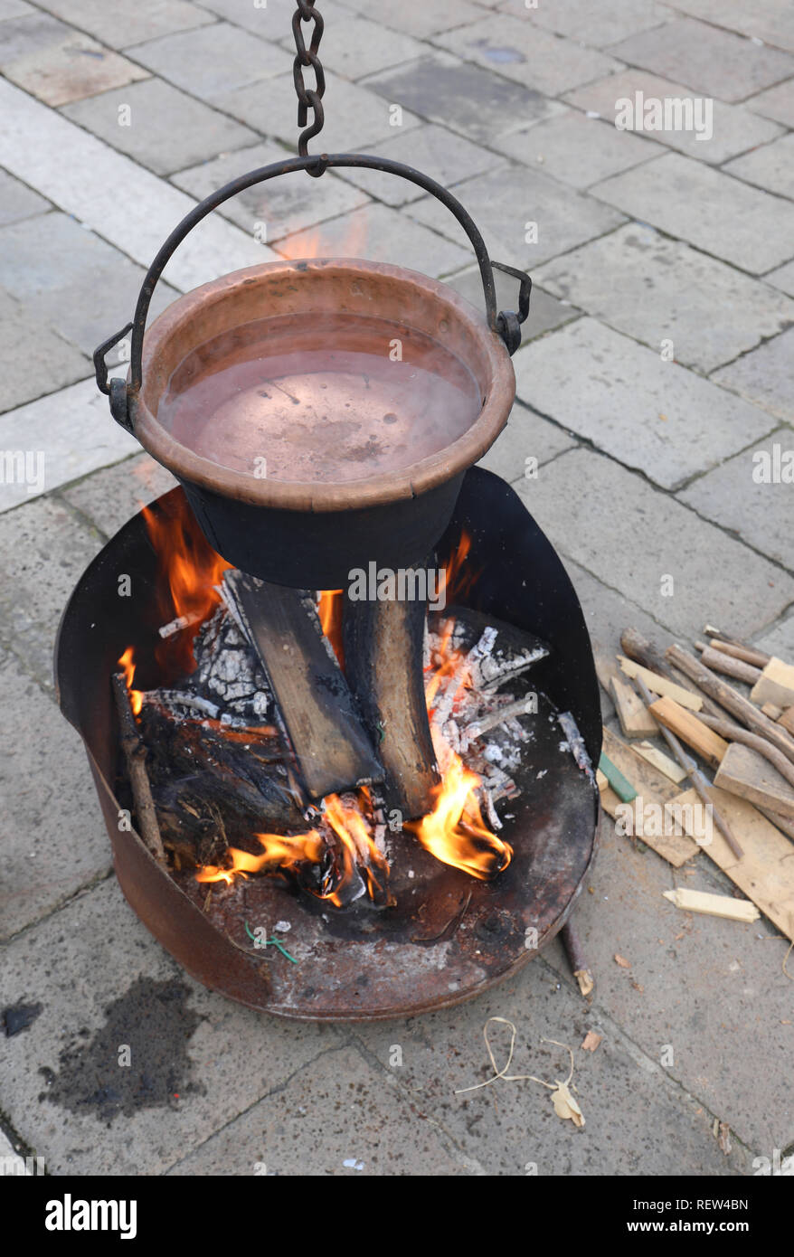 ancient copper cauldron burns over a fire during a medieval historical ...