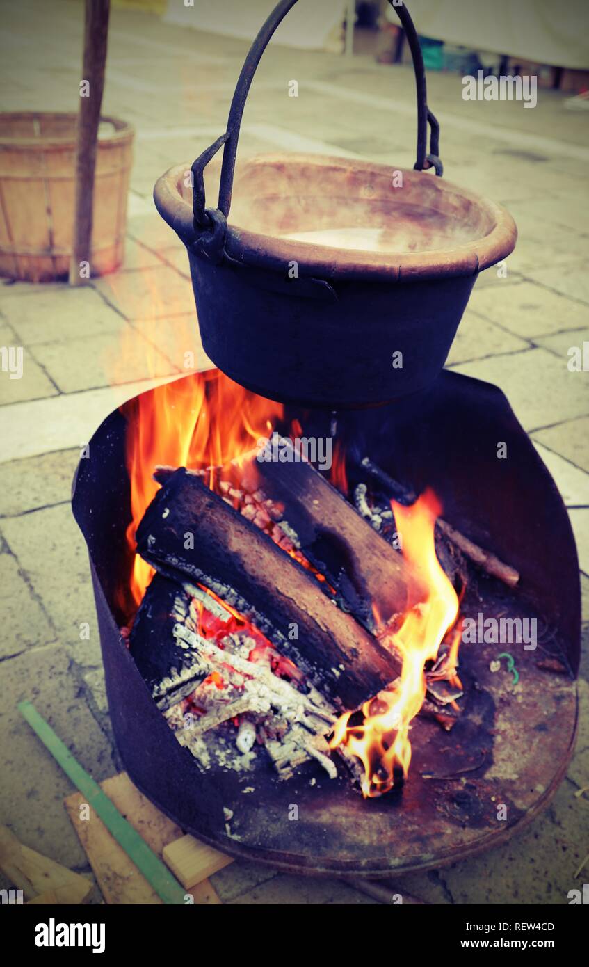 ancient copper cauldron full of boiling water with fire made from logs ...