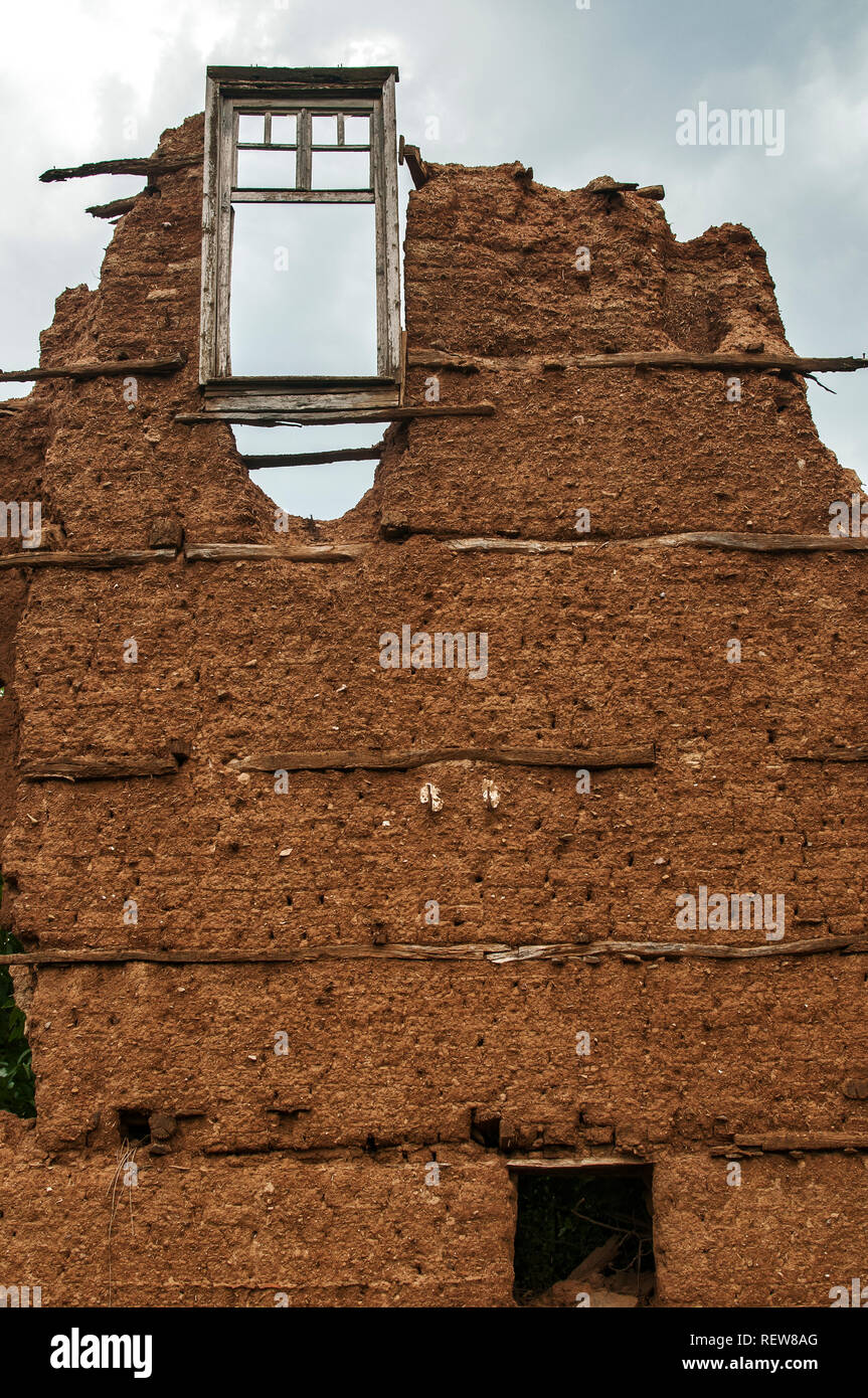 Brick wall with adobe clay plaster and broken wooden window frame ...