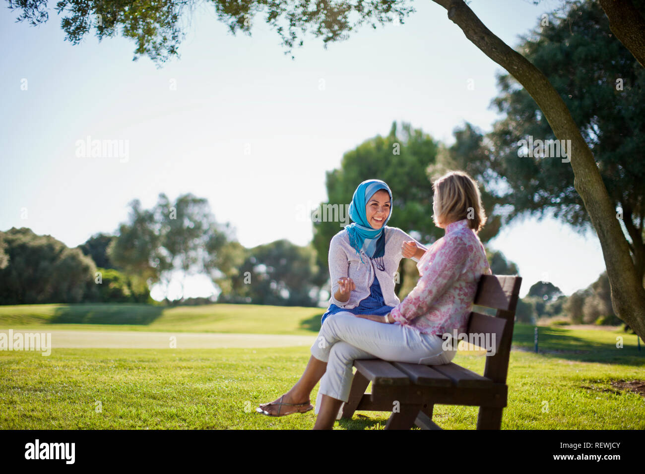 Happy friends talking together in a serene green park Stock Photo - Alamy