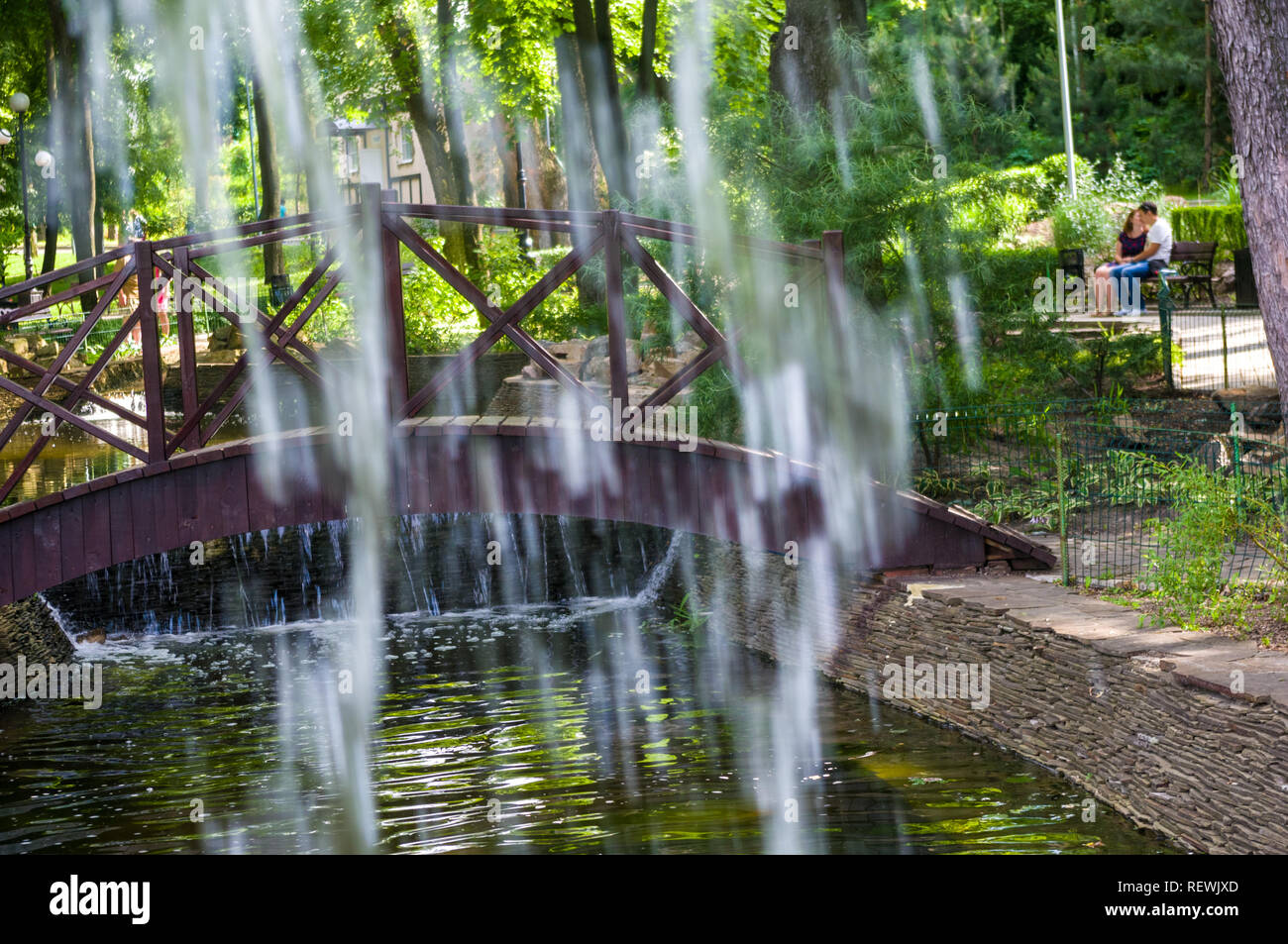 transparent falling water vertical flows against a blue sky and green ...