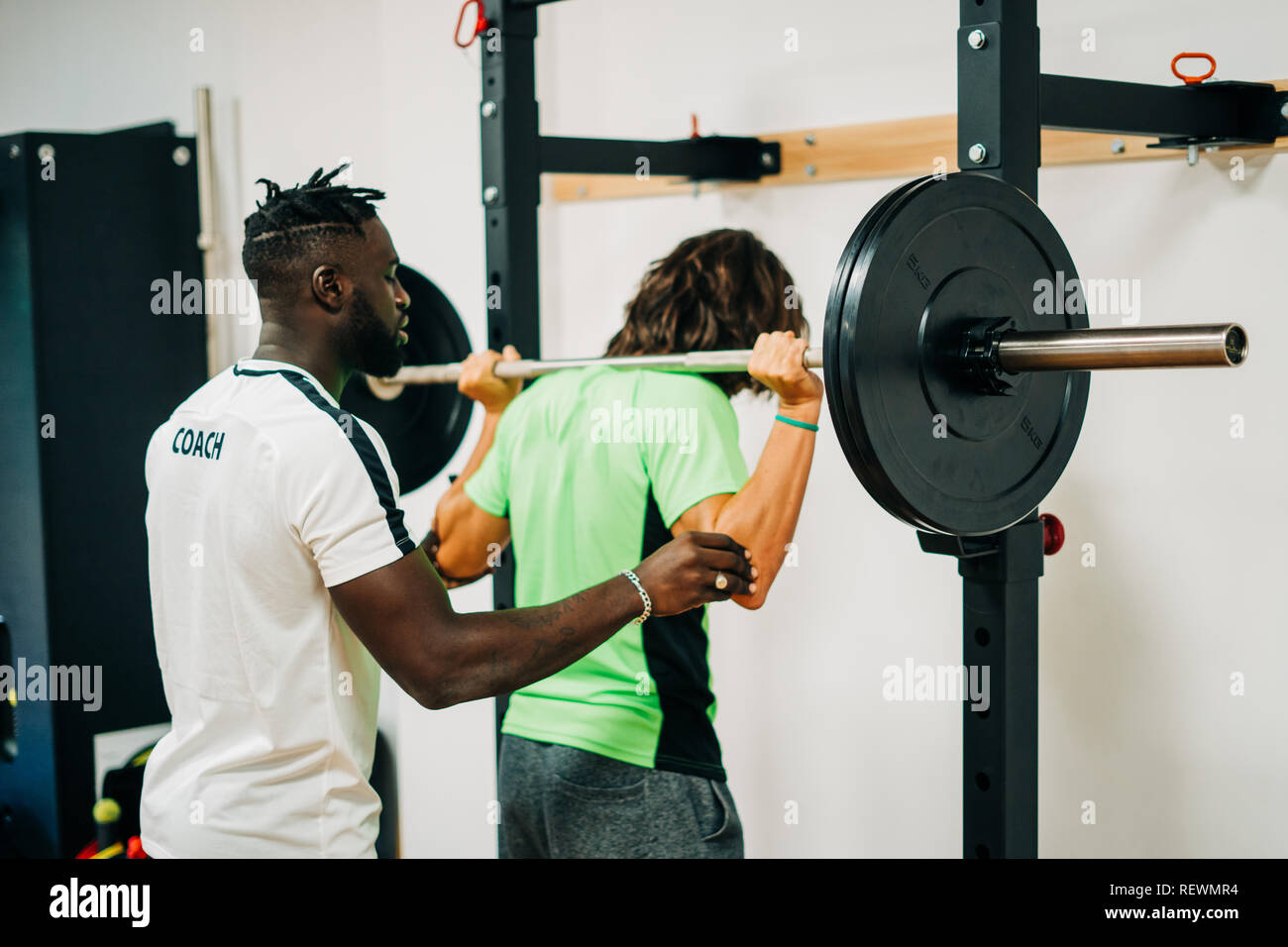 Black man coach training barbell with his patient in gym Stock Photo ...