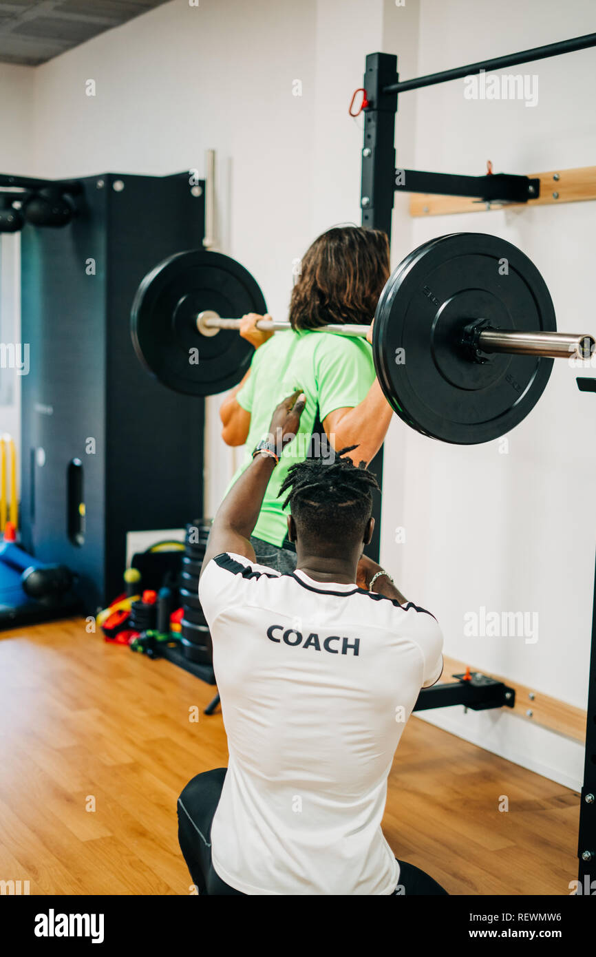 Black man coach training barbell with his patient in gym Stock Photo ...