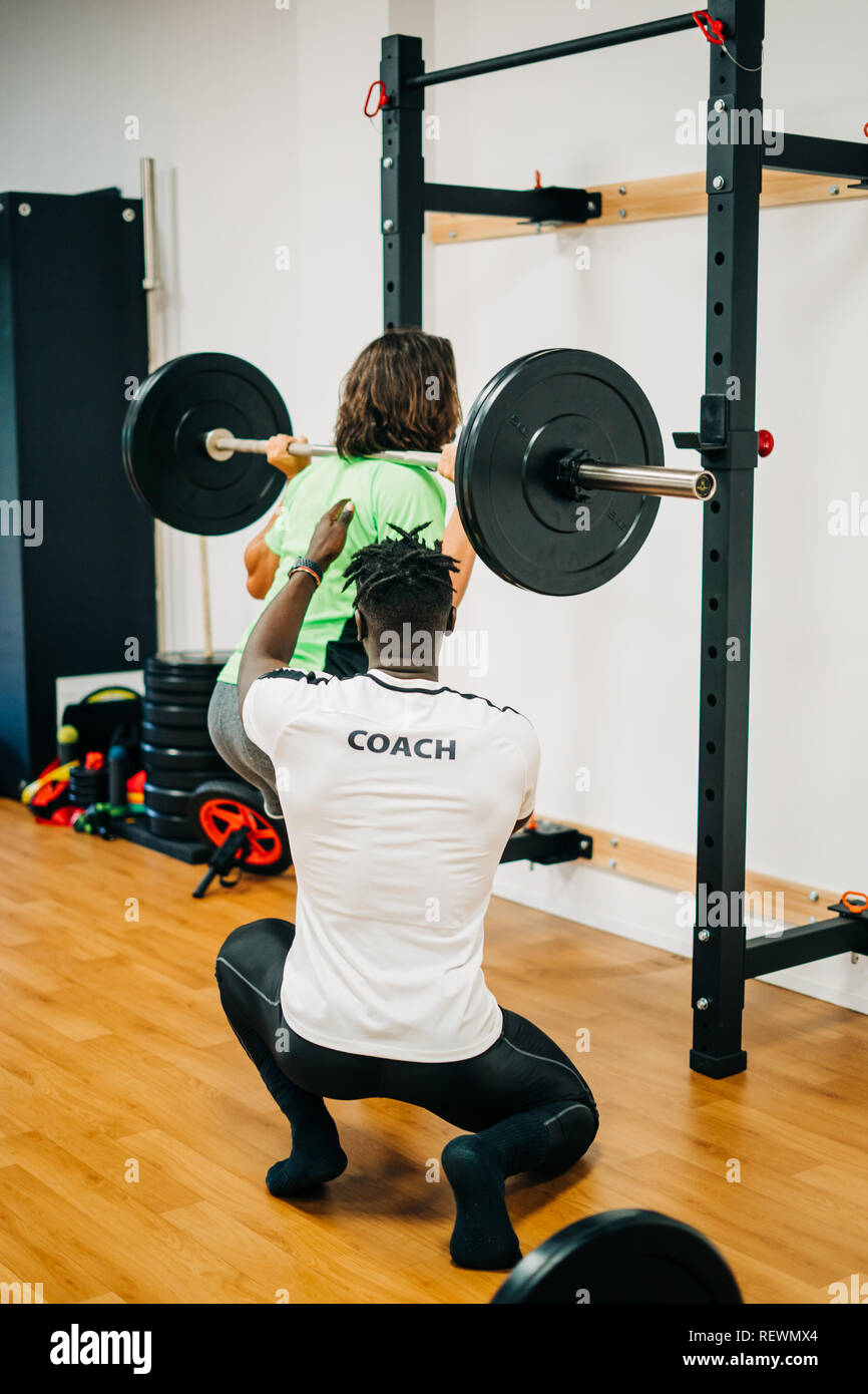 Black man coach training barbell with his patient in gym Stock Photo ...