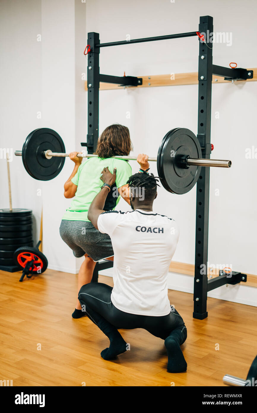 Black man coach training barbell with his patient in gym Stock Photo ...
