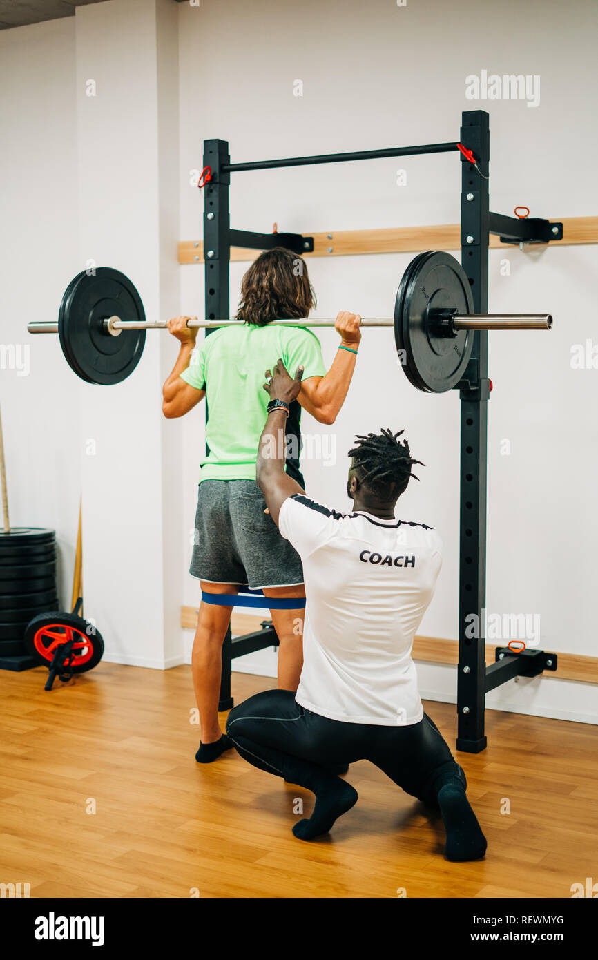 Black man coach training barbell with his patient in gym Stock Photo ...