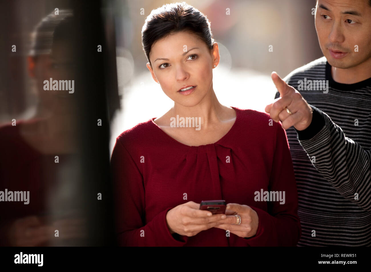 Man points out directions to a young woman holding her phone Stock ...