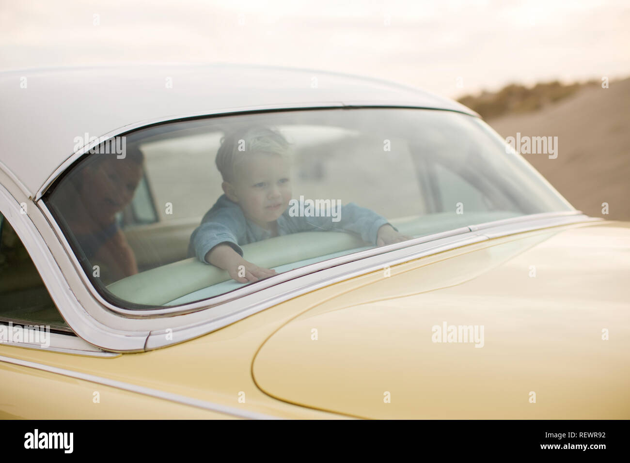 Boy looking out rear car window Stock Photo - Alamy