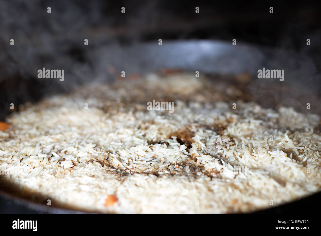 cooking Rice for pilaw or paella in iron cauldron over open fire. Smoke ...