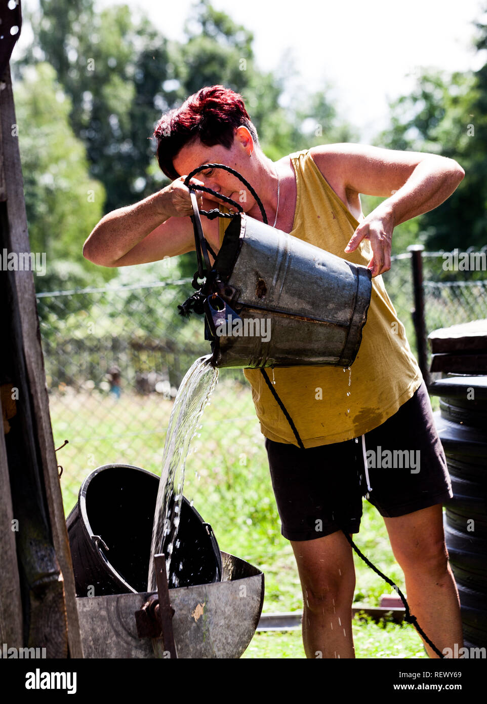 A hardworking woman pouring water to the shallow basin. The housewife ...