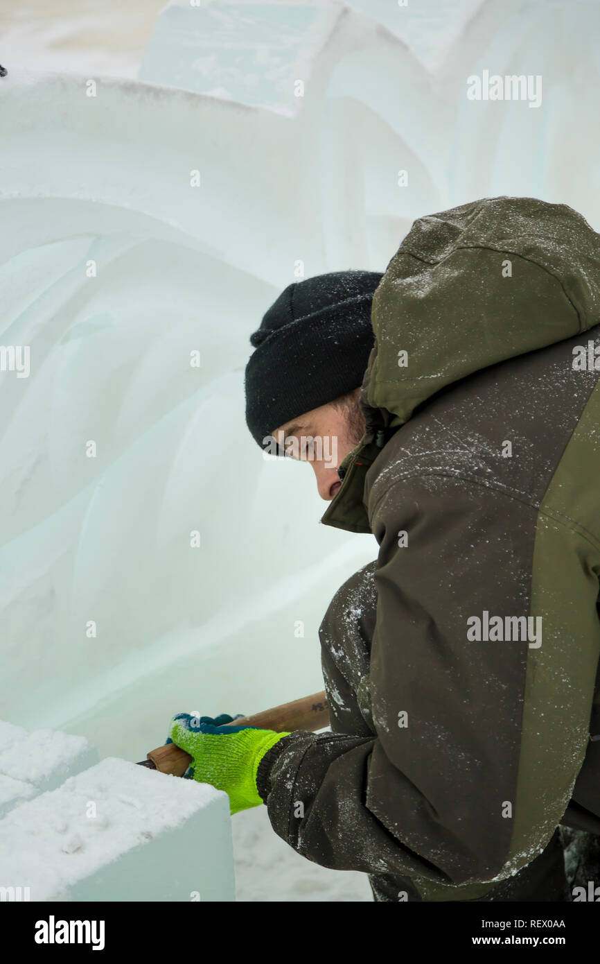 The sculptor cuts an ice figure out of an ice block with a chisel Stock ...