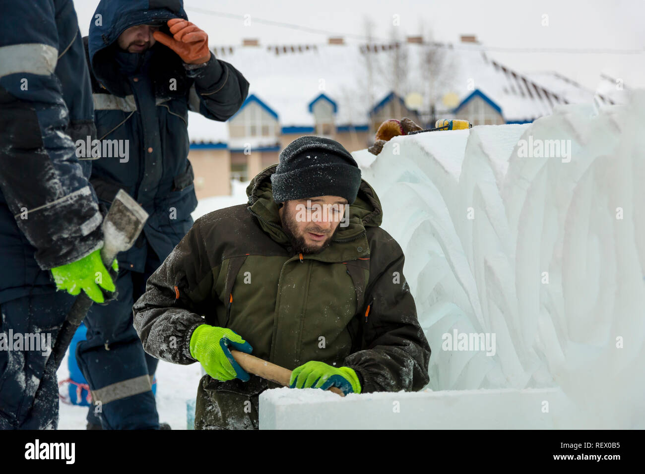 The sculptor cuts an ice figure out of an ice block with a chisel Stock ...