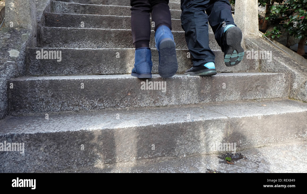 Two people climbing up a concrete stairs. Only the lower legs are ...
