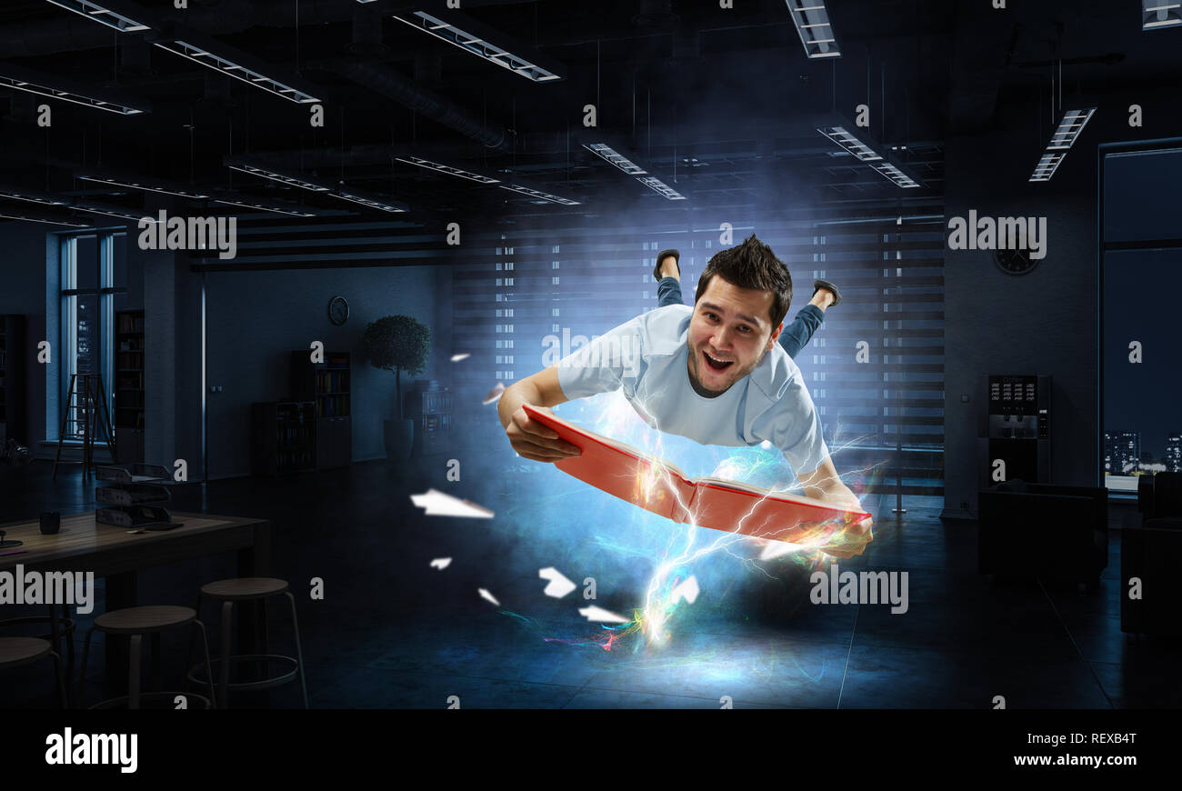 Funny guy with book in hands levitating in air. Mixed media Stock Photo ...