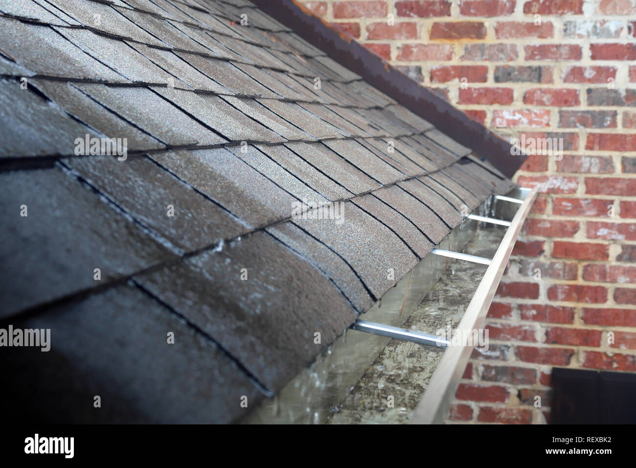 Working gutter on a brick house with flowing water into the grass ...