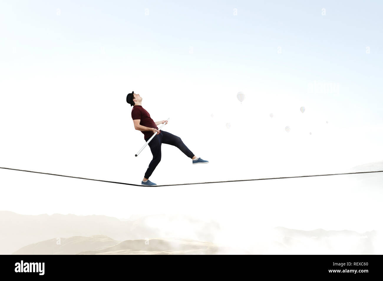 Ropewalker in black hat walking rope high in sky . Mixed media Stock ...