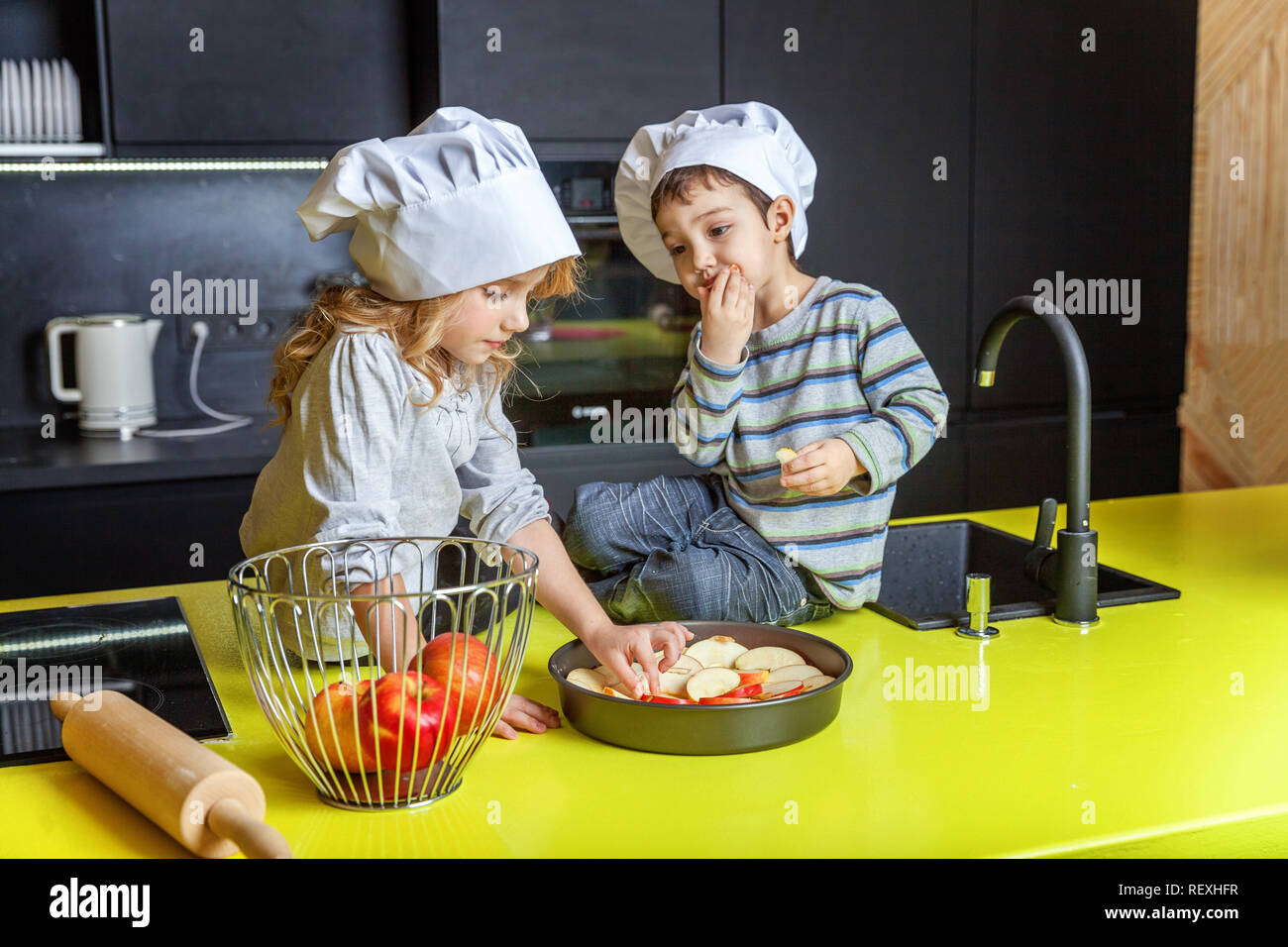 Little kids girl and boy with chef hat preparing bake homemade apple ...