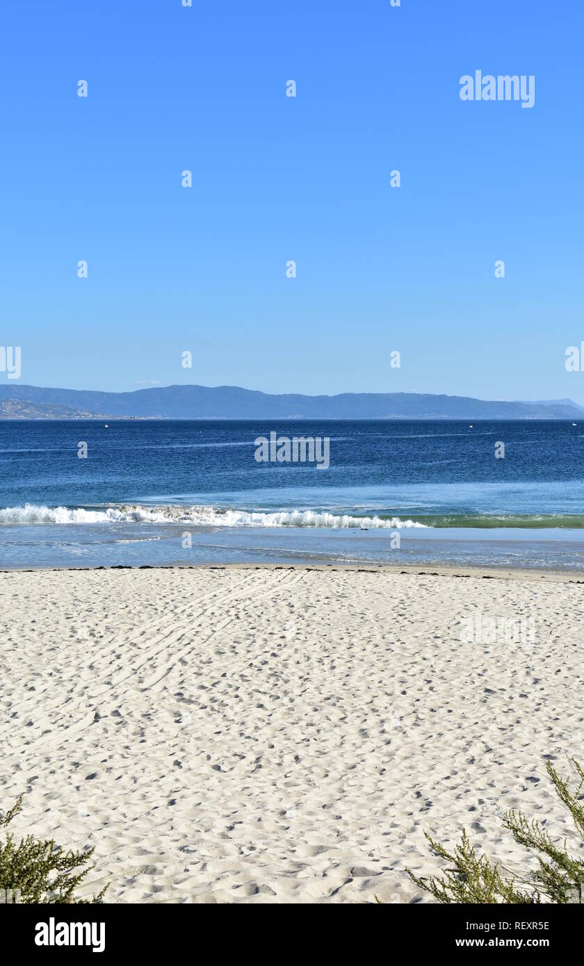 Beach with bright sand and blue sea with small waves and foam. Clear ...