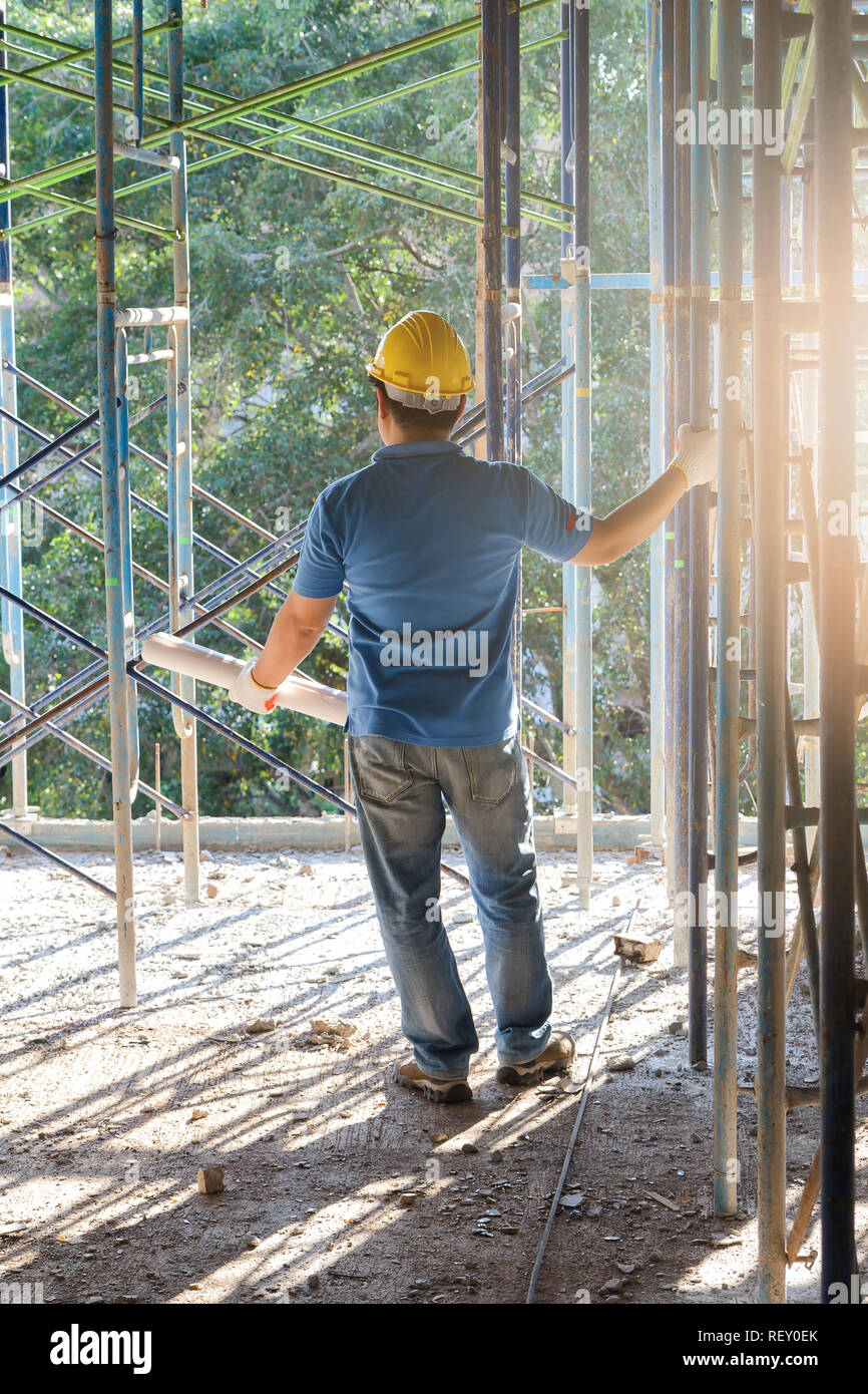 Engineer with blueprint in building construction site Stock Photo - Alamy
