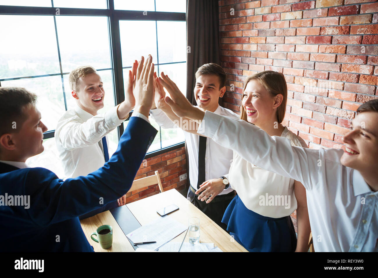 Group of happy young business team celebrating and high fiving each ...
