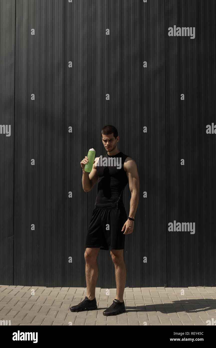 Sport model man drinking water from a plastic bottle on gray background ...