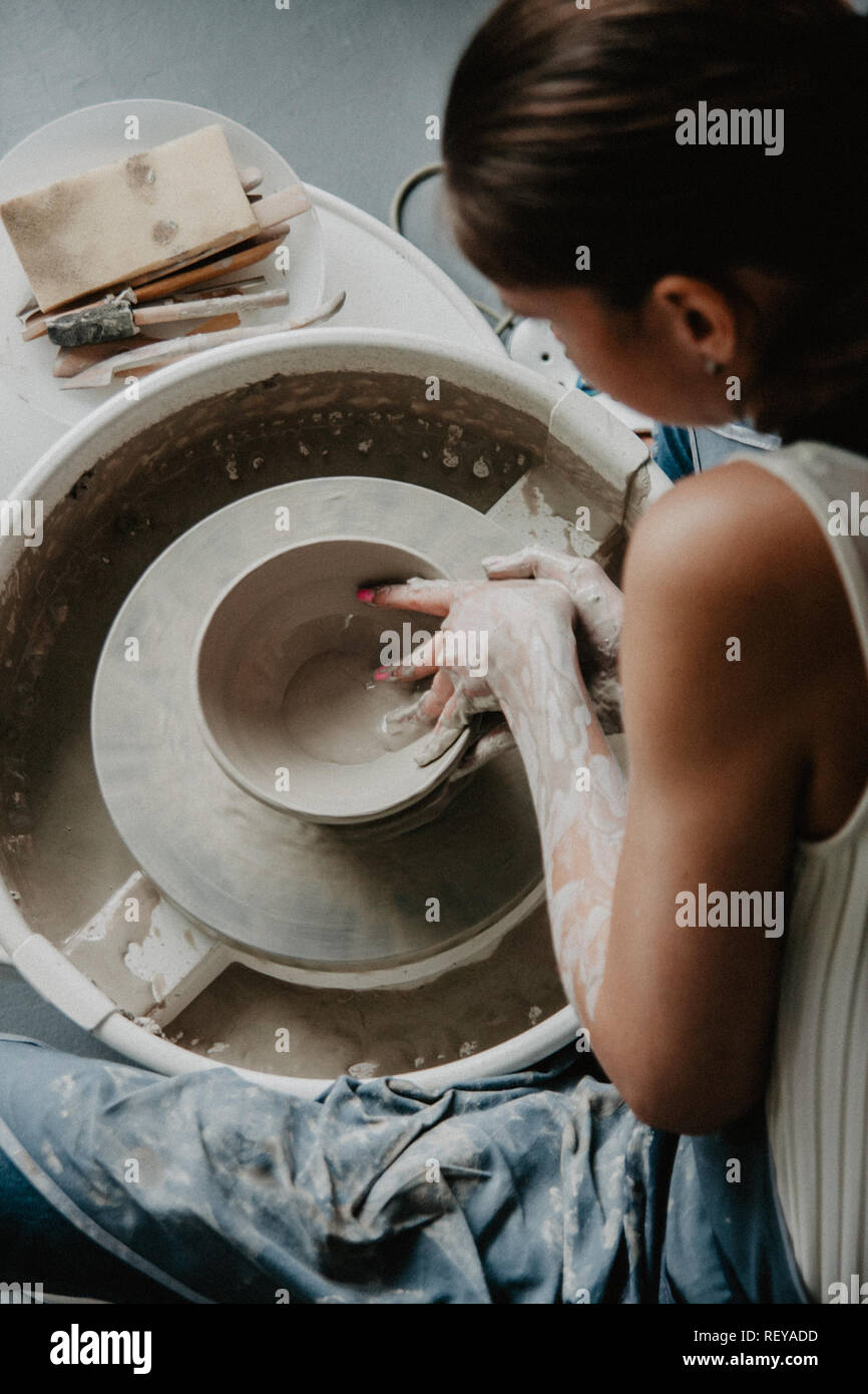 Creating a jar or vase of white clay close-up. Woman hands making clay ...
