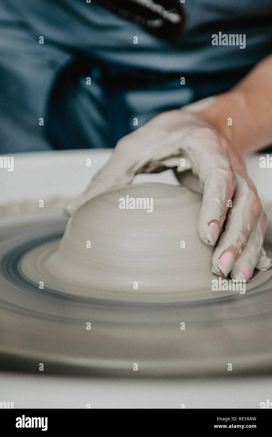Creating a jar or vase of white clay close-up. Woman hands making clay ...