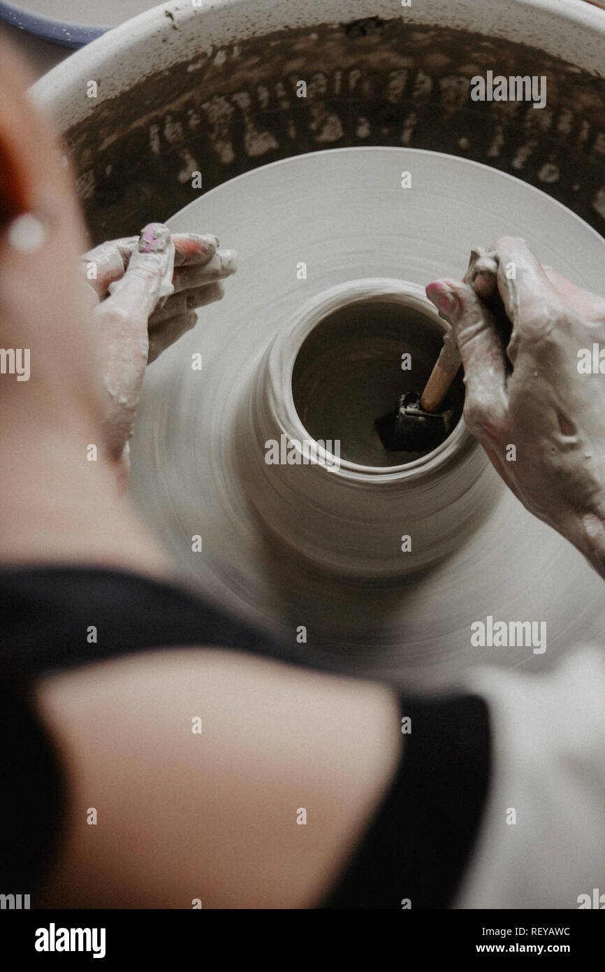 Creating a jar or vase of white clay close-up. Woman hands making clay ...