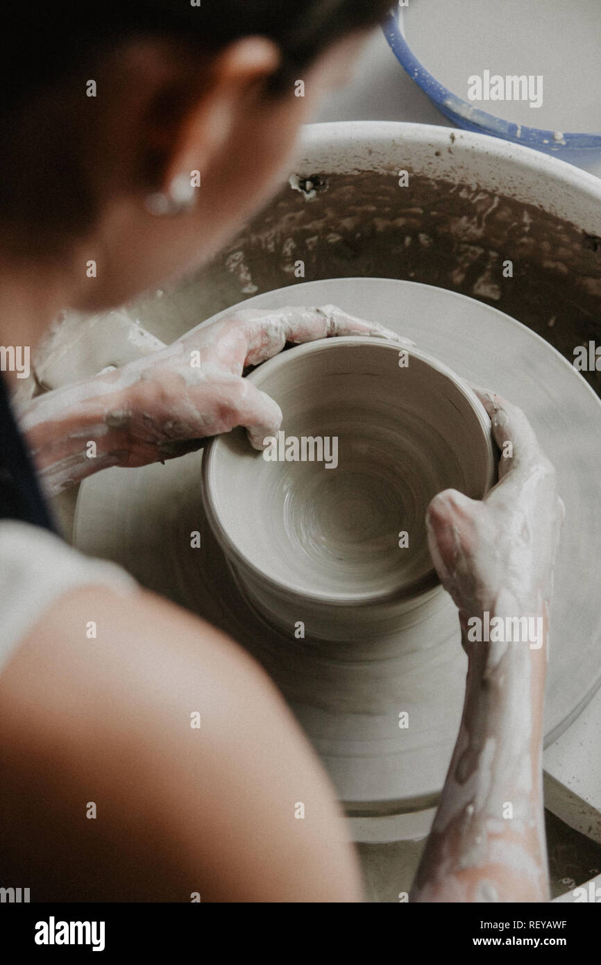 Creating a jar or vase of white clay close-up. Woman hands making clay ...