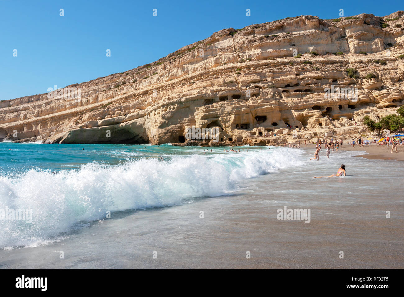 Sandy beach and sandstone cliffs with caves at Matala. South coast ...