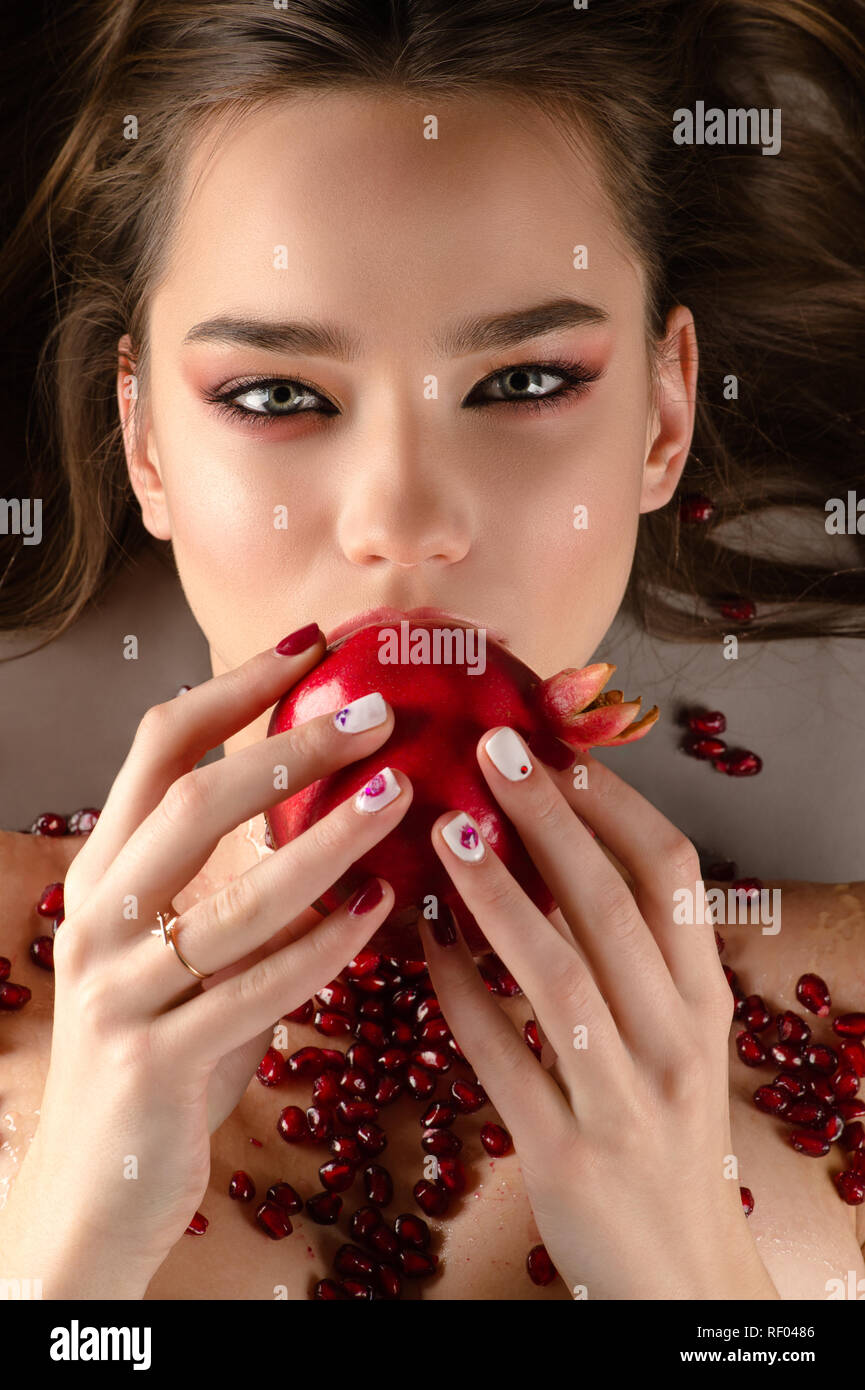 beautiful brunette girl eating pomegranate, from above Stock Photo - Alamy