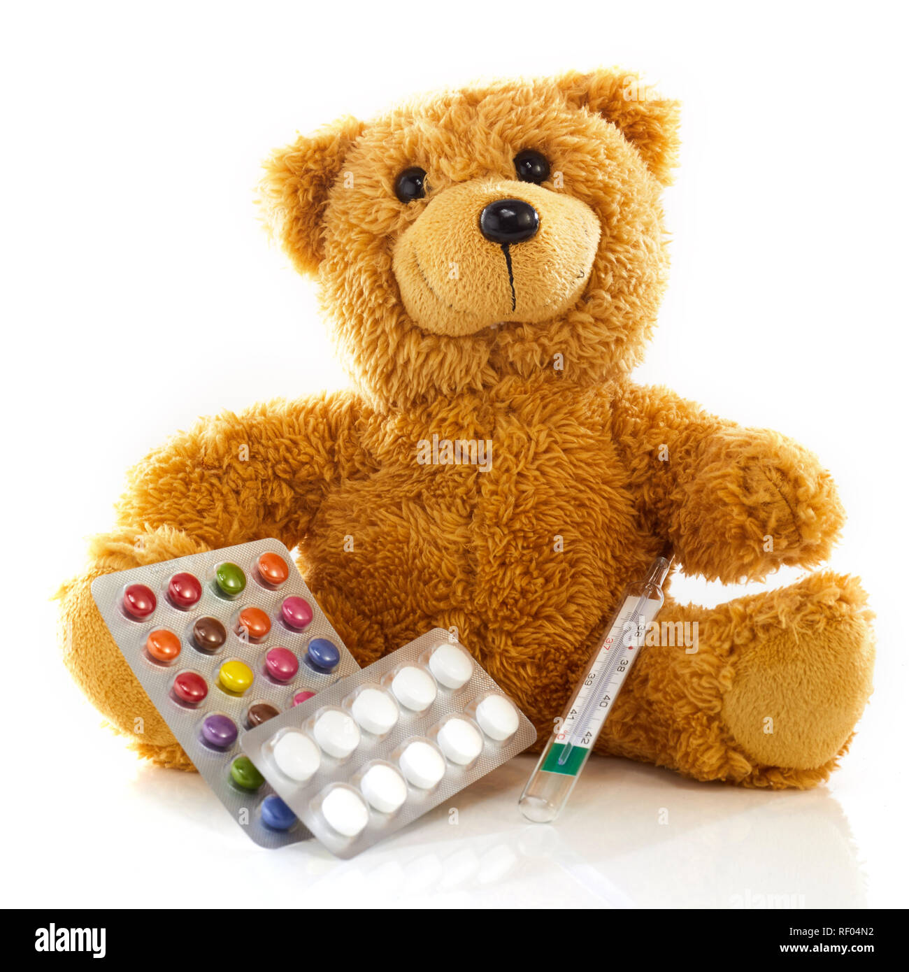 Sick toy teddy bear with blister packs of tablets and a thermometer ...
