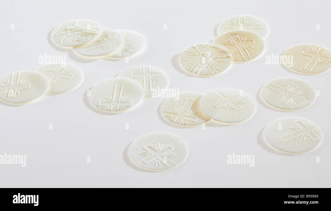 Scattered sacramental Hosties on a white background symbolic of the ...